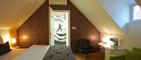 Quarto com uma cama, escrivaninha, cadeira e sofá verde.