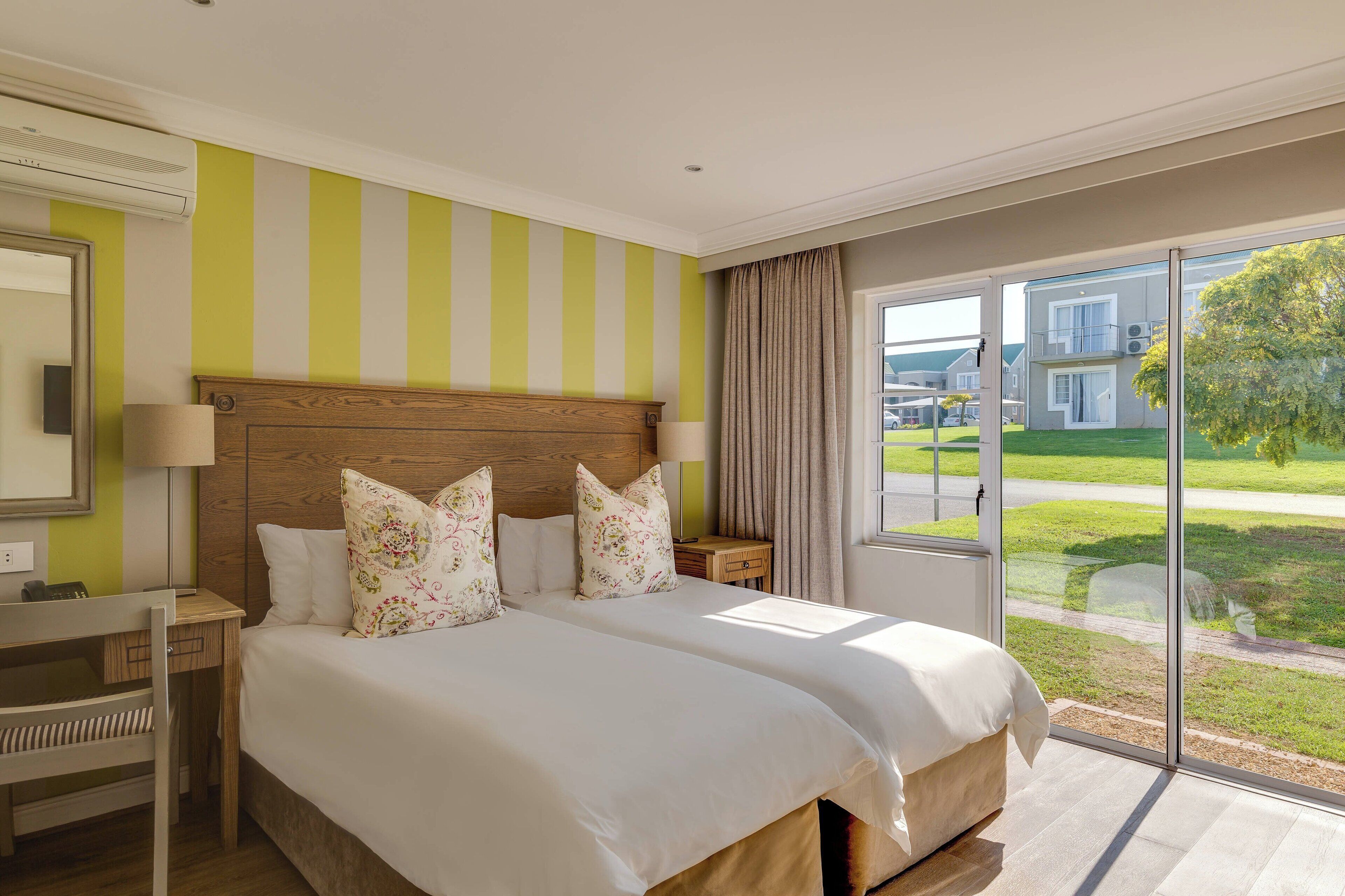 Quarto de hotel com uma cama grande, uma escrivaninha e vista para o exterior.