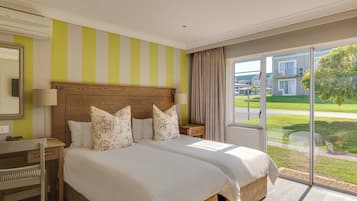 Quarto de hotel com uma cama grande, uma escrivaninha e vista para o exterior.