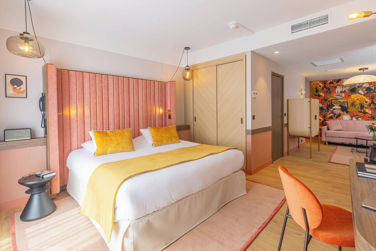 Quarto de hotel com uma cama grande, uma escrivaninha, uma cadeira e um guarda-roupa.