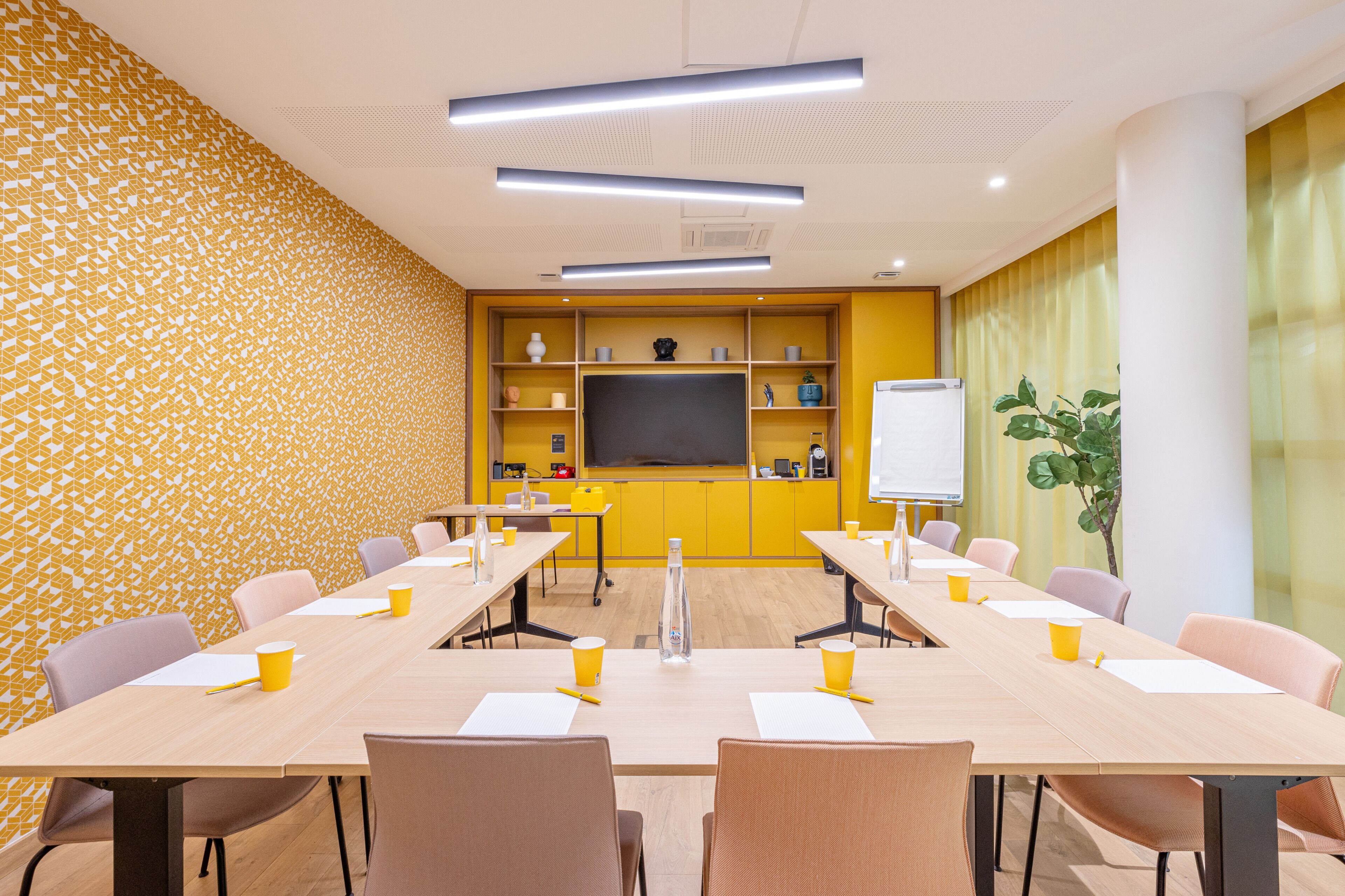 Uma sala de conferência com uma mesa comprida, cadeiras, um quadro branco e parede estampada.