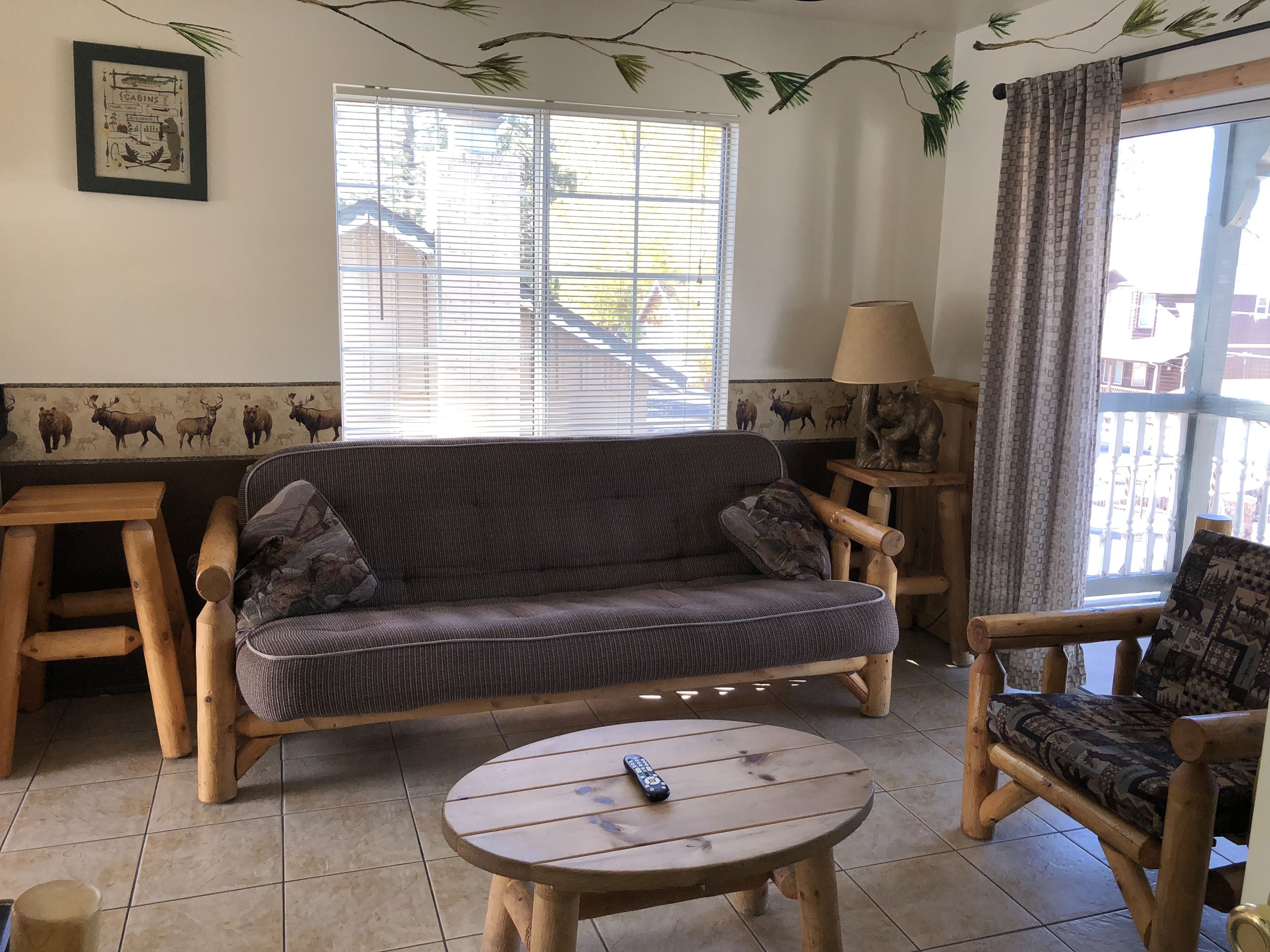 Uma sala de estar acolhedora com um sofá, uma cadeira de madeira, uma mesa redonda de madeira e um abajur.