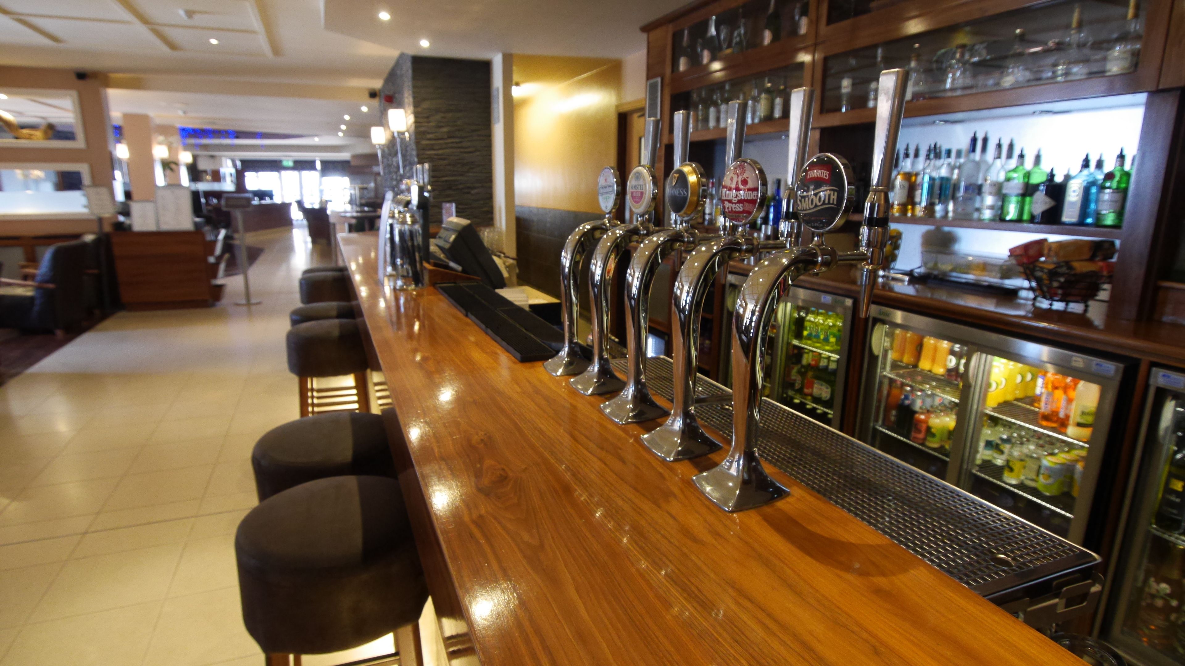 Uma área de bar com várias torneiras e banquetas.