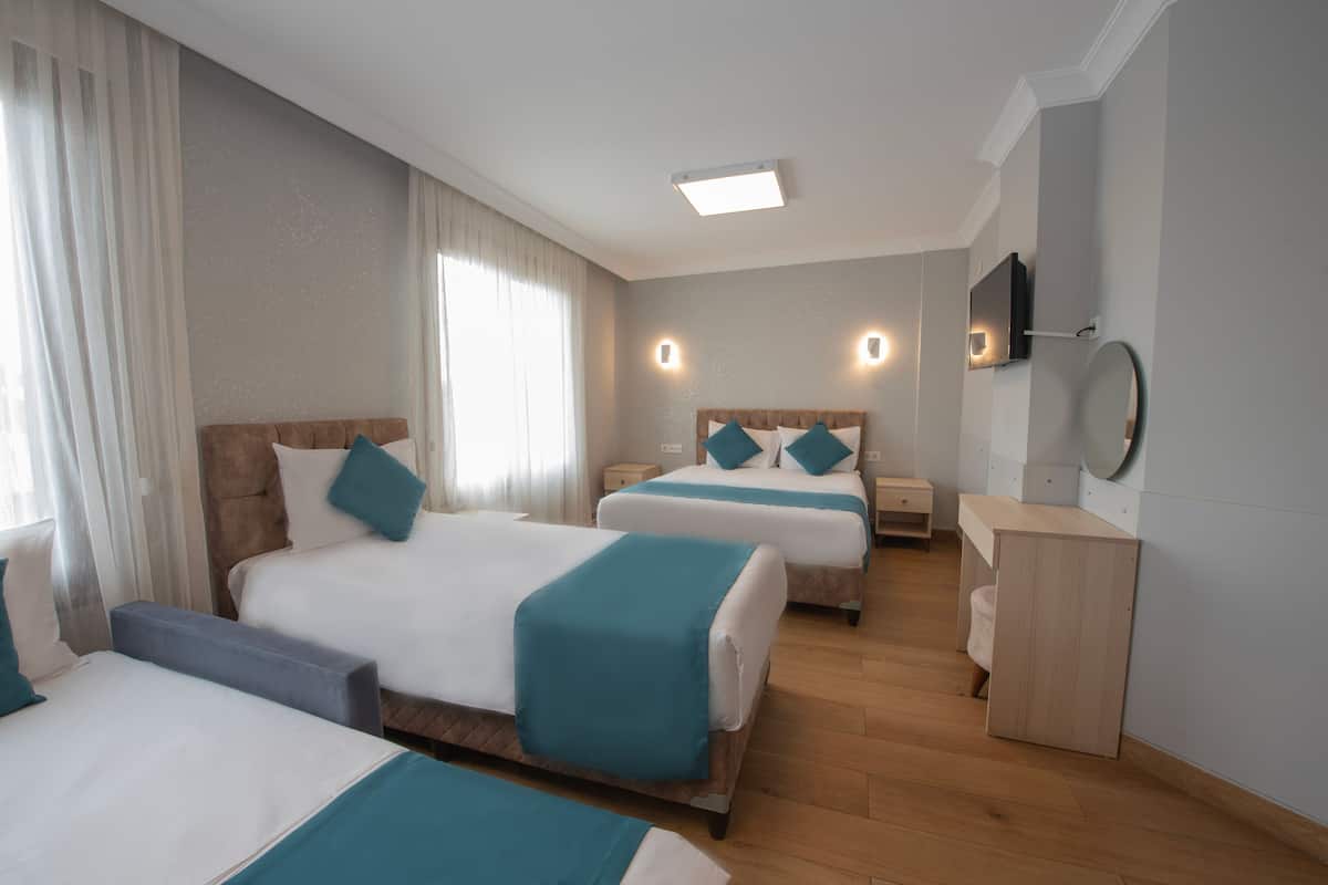 Quarto de hotel com duas camas, uma escrivaninha, uma cadeira, televisão e um espelho.