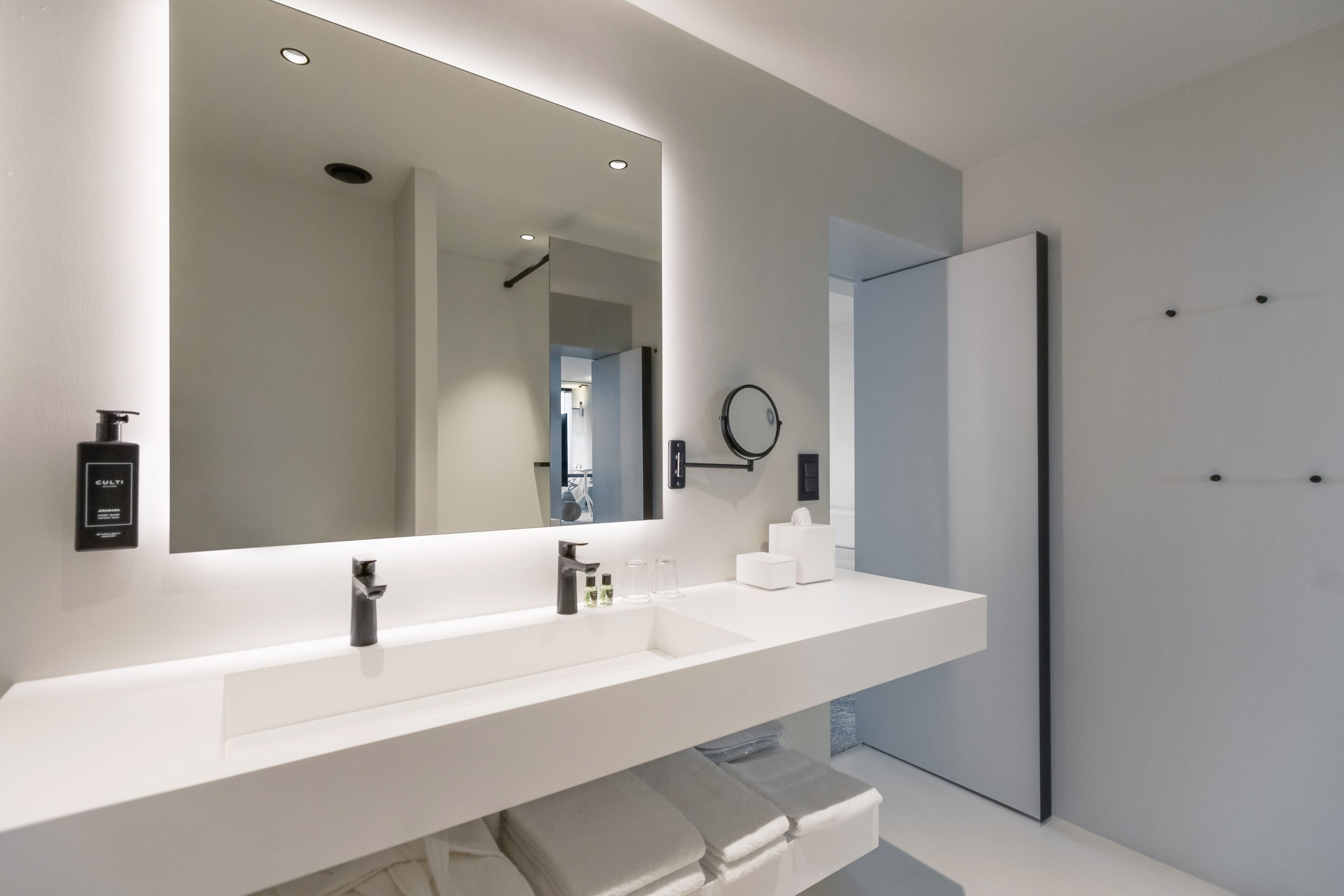 Uma casa de banho moderna com um espelho grande, uma sanita branca e um porta-toalhas.