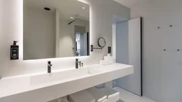 Uma casa de banho moderna com um espelho grande, uma sanita branca e um porta-toalhas.