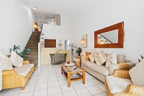 Sala de estar com sofá, mesa de centro e cadeiras de vime.