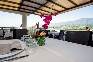 Mesa posta para refeição com vista para montanhas ao fundo.