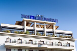 Um hotel com uma placa de destaque que diz "Michelangelo Hotel" e um design arquitetônico moderno, com sacadas e grandes janelas.