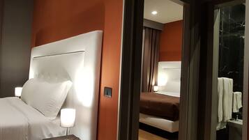 Quarto de hotel com cama grande, abajures, espelho e vista para outro quarto.