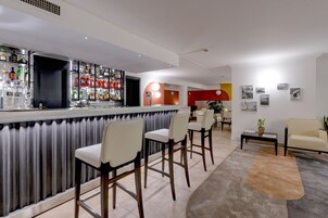 Uma área de bar com balcão, assentos e uma parede com quadros.