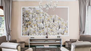 Uma sala de estar com um grande quadro floral, um candelabro e dois sofás.