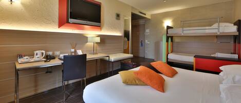 Quarto de hotel com cama, escrivaninha com computador, televisão e beliche.
