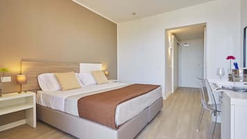 Quarto de hotel moderno com cama, mesa de cabeceira, luminária e escrivaninha com cadeira.
