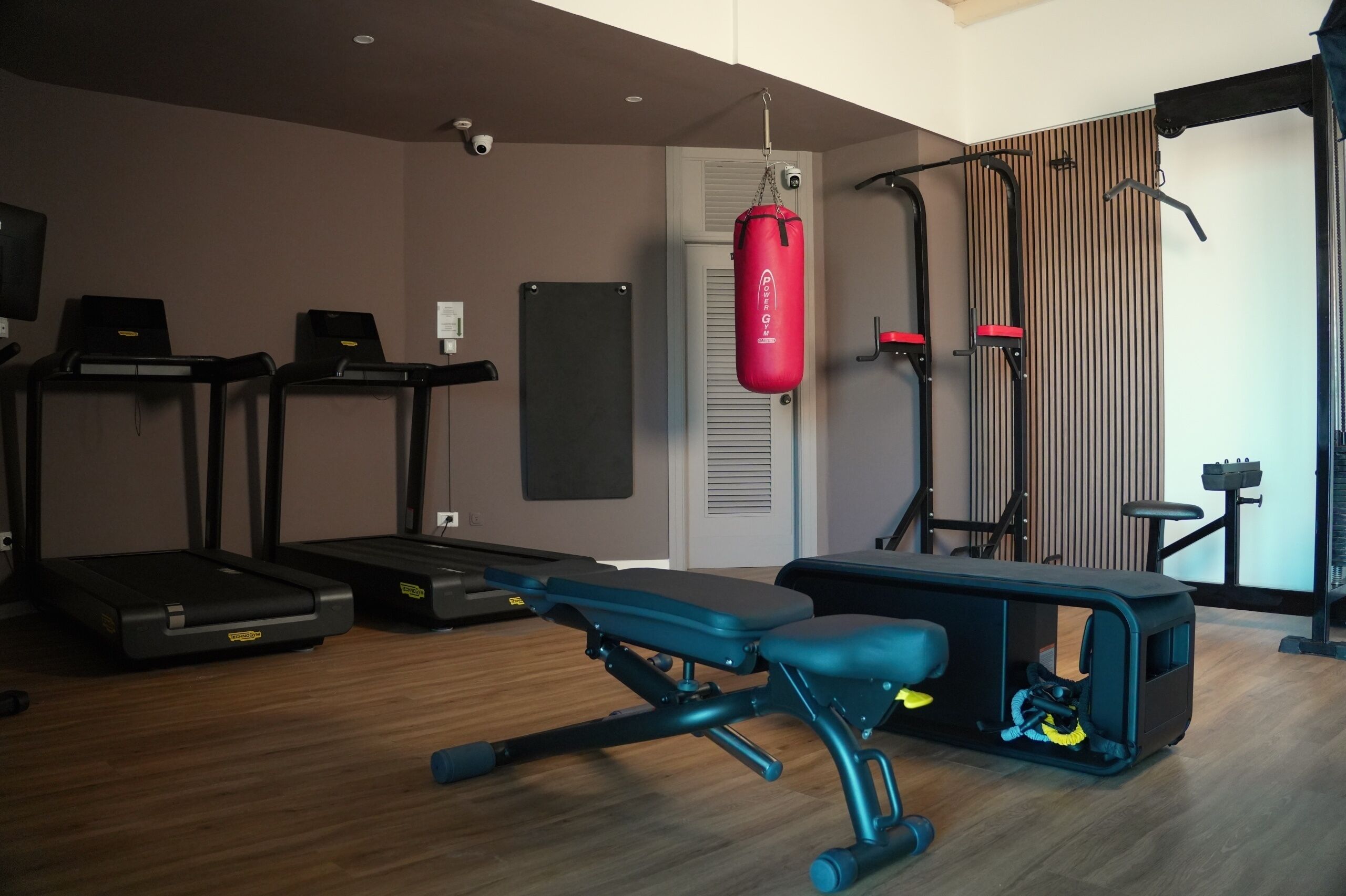 Uma academia com esteiras, saco de pancadas e equipamentos de ginástica.