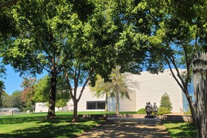Uma trilha leva a um edifício de arquitetura moderna, cercado por árvores exuberantes.