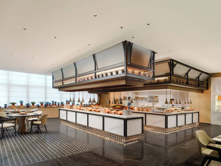 Um restaurante moderno com uma ilha central, assentos ao redor e uma área de cozinha visível ao fundo.