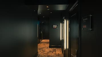 Um corredor com uma placa indicando uma estação de metrô, uma porta com a inscrição 'Queens' e um piso com padrão.