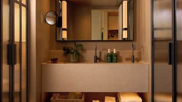 Uma casa de banho moderna com um espelho grande, uma sanita com artigos de higiene e um porta-toalhas.