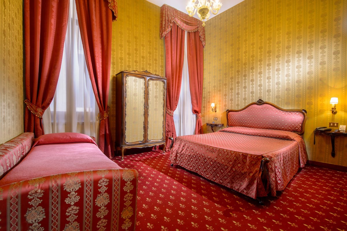 Quarto com duas camas, um guarda-roupa e um candelabro.