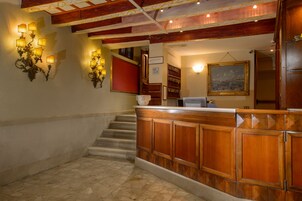 Uma área de recepção com balcão de madeira, escada e luminárias fixadas na parede.