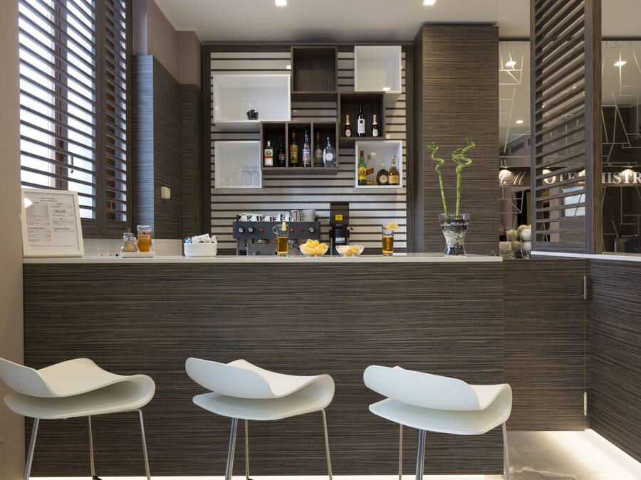 Uma cozinha moderna com área de bar, com balcão, banquetas, armários de madeira e espaço para vinhos.