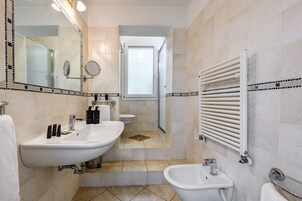 Uma casa de banho moderna com lavatório, bidé e espelho brancos.