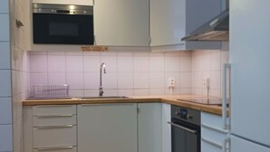 Uma cozinha compacta com armários brancos, micro-ondas, pia e lava-louças.