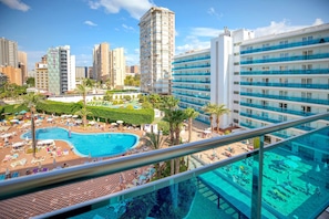 Um hotel com piscina no terraço, vários andares e vista para a cidade.