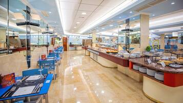 Uma área de buffet com vários balcões de serviço, cadeiras azuis e piso polido.