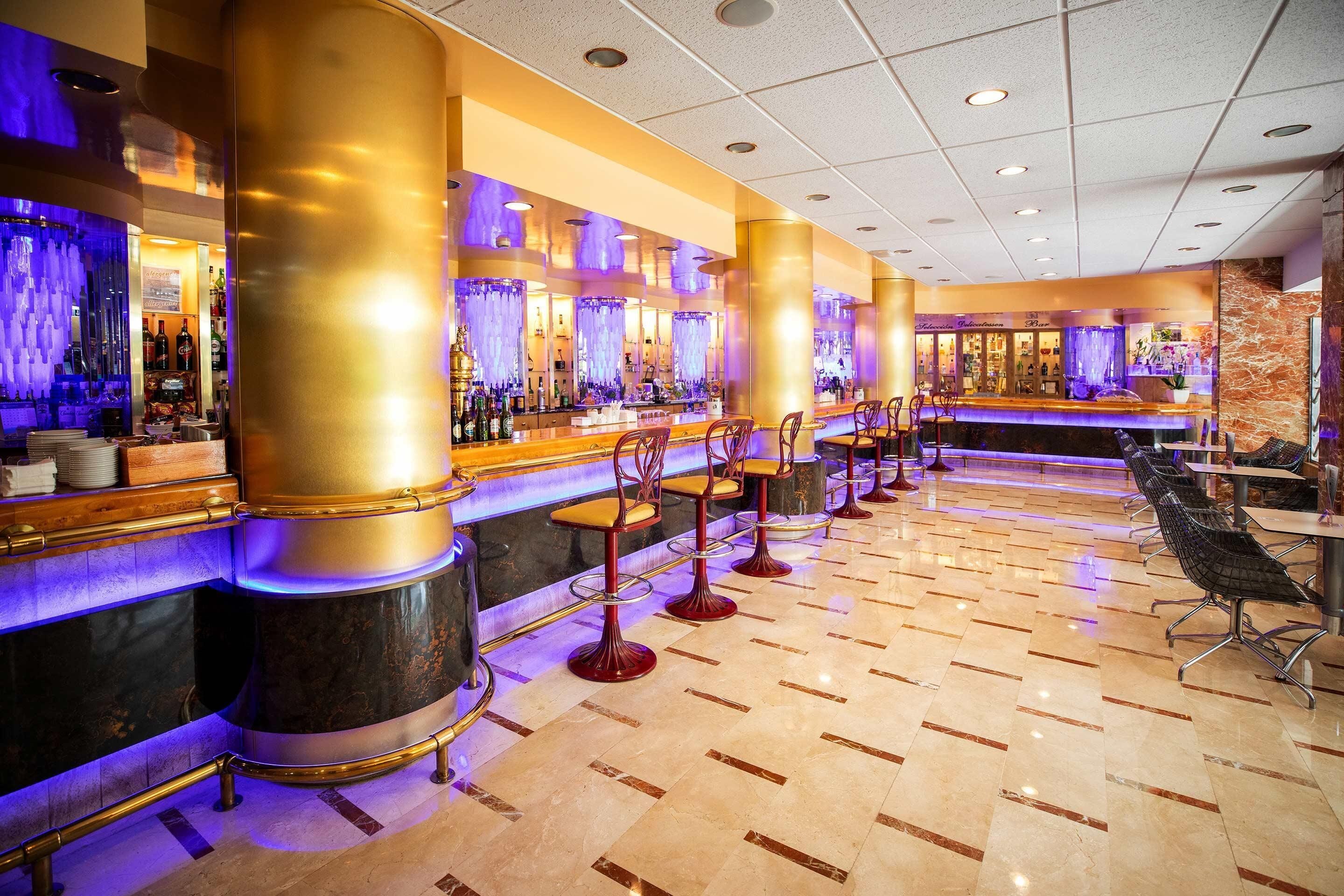 Uma área de bar com vários bancos, um balcão e chão de mármore.