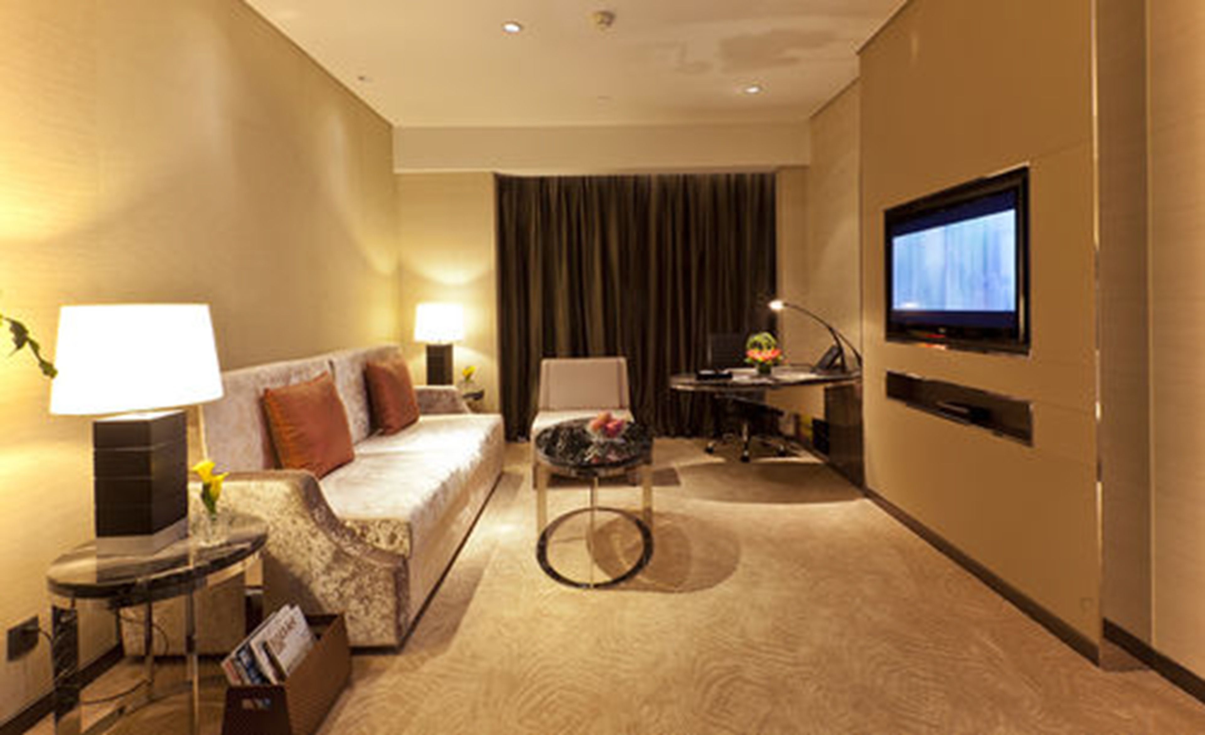 Quarto de hotel com uma cama, uma mesa, uma televisão e um abajur.