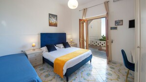 Quarto com cama, mesas de cabeceira, uma cadeira e vista para o exterior.