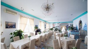 Uma sala de jantar com várias mesas e cadeiras, um candelabro e um chão colorido.