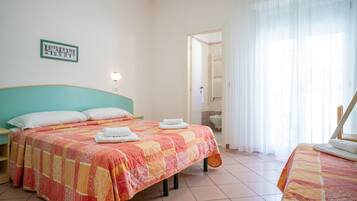 Quarto de hotel com duas camas, banheiro e vista para o mar.