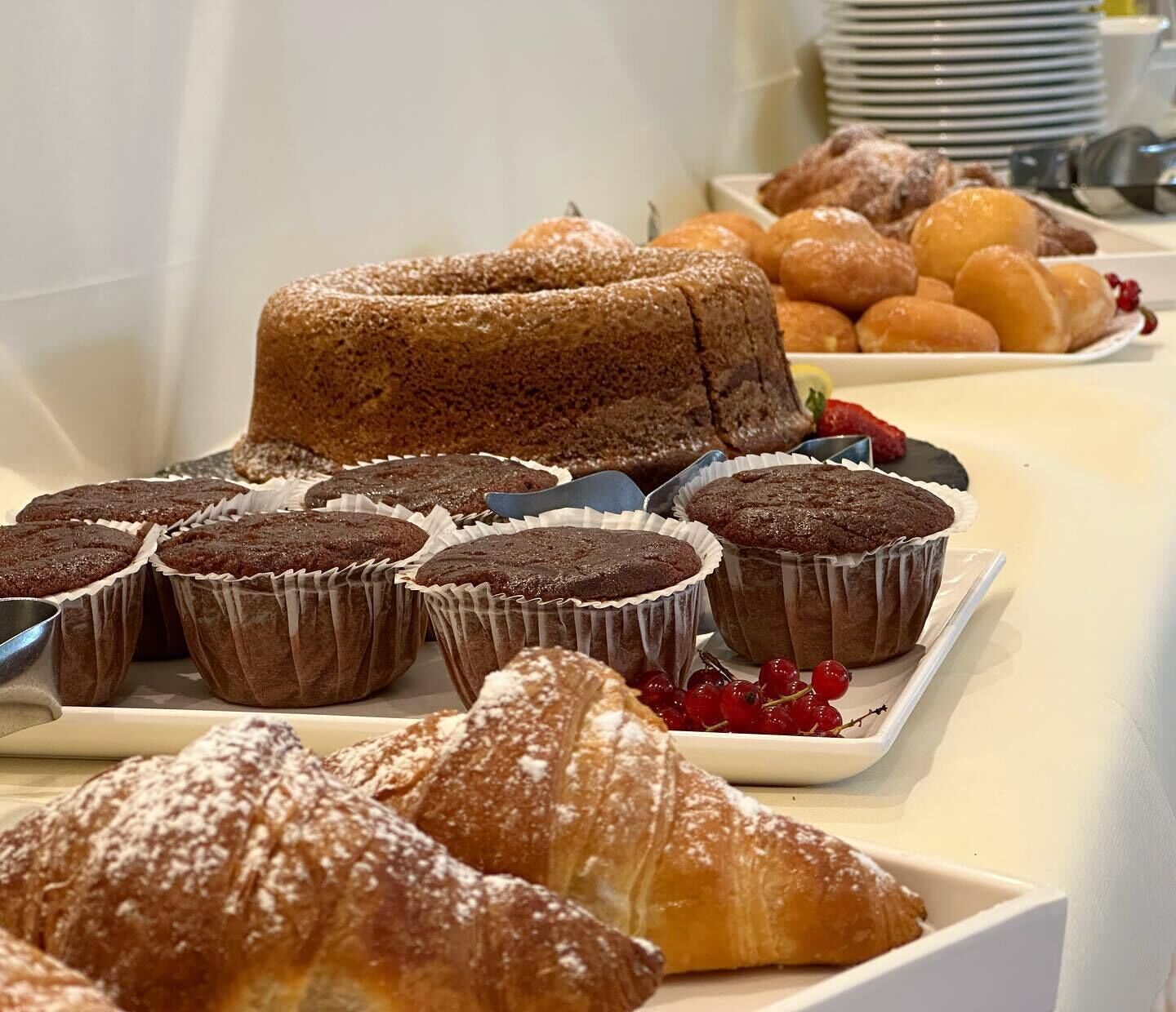 Buffet com diversos produtos de panificação, incluindo bolos, muffins e doces.