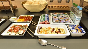 Uma mesa de buffet com diversos alimentos, incluindo frutas, legumes e produtos embalados.