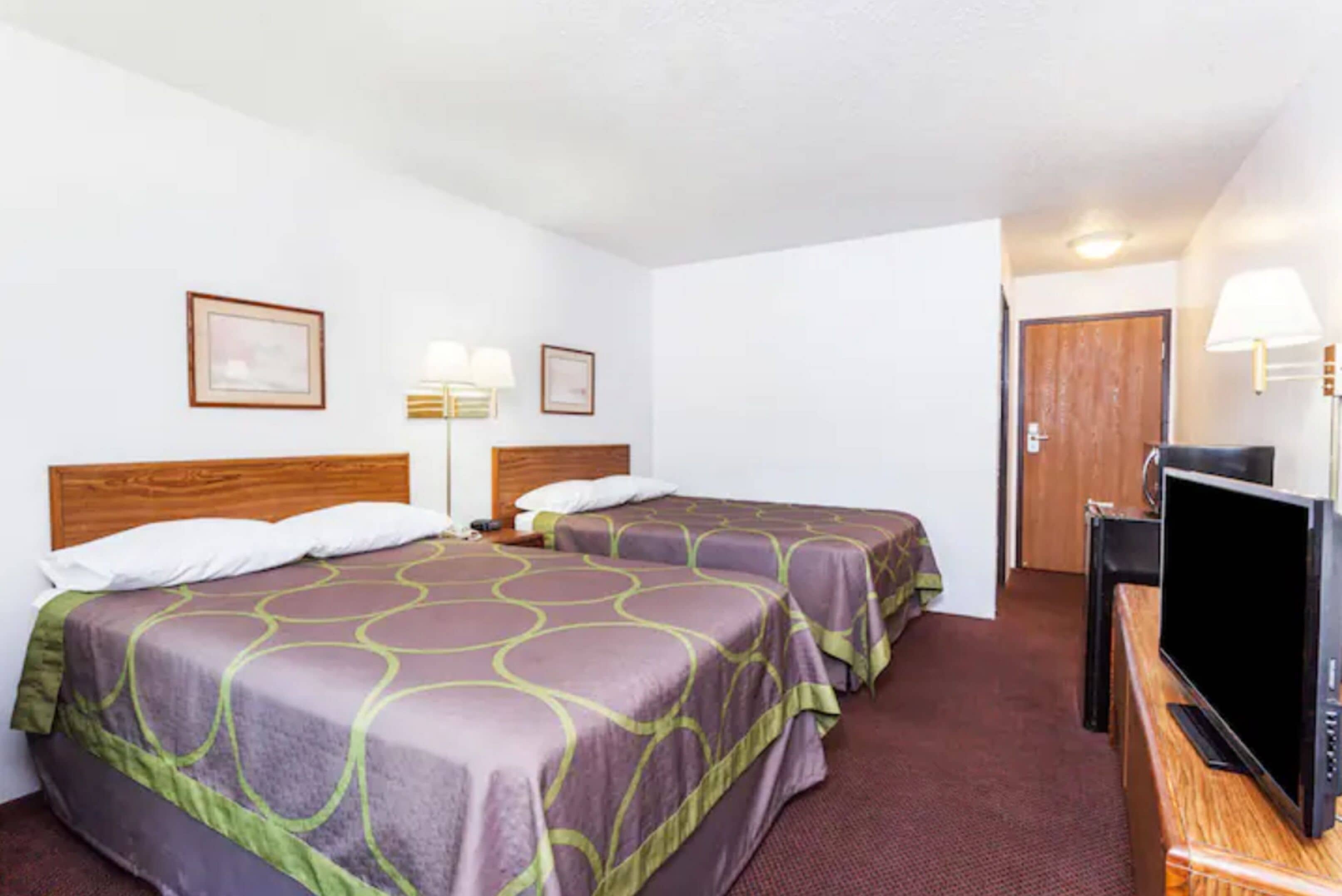 Quarto de hotel com duas camas, televisão e escrivaninha.
