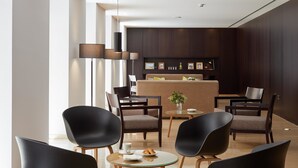 Um saguão de hotel moderno com balcão de recepção, área de estar e mesa de centro com doces.