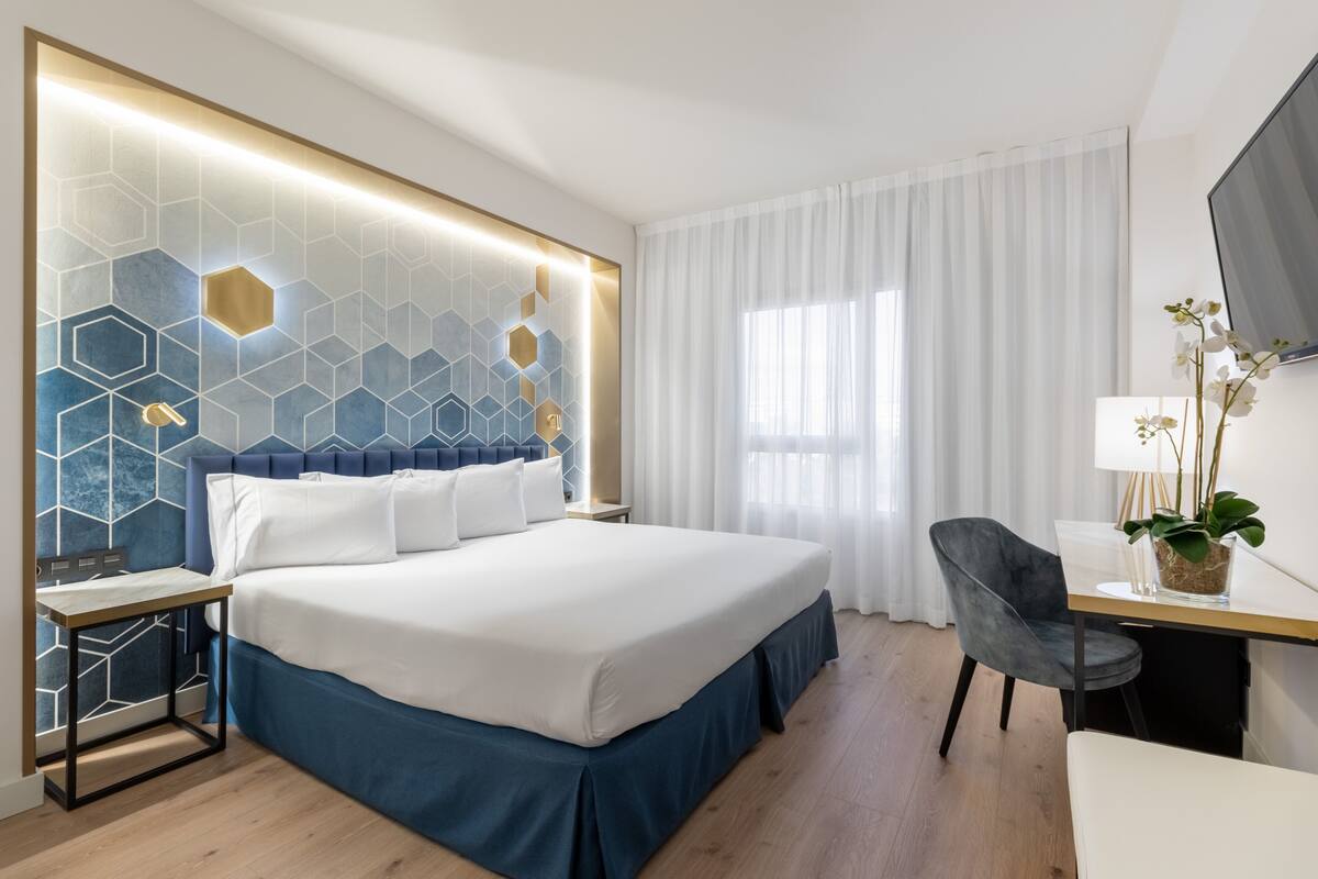 Quarto de hotel moderno com uma cama grande, uma mesa e uma cadeira.