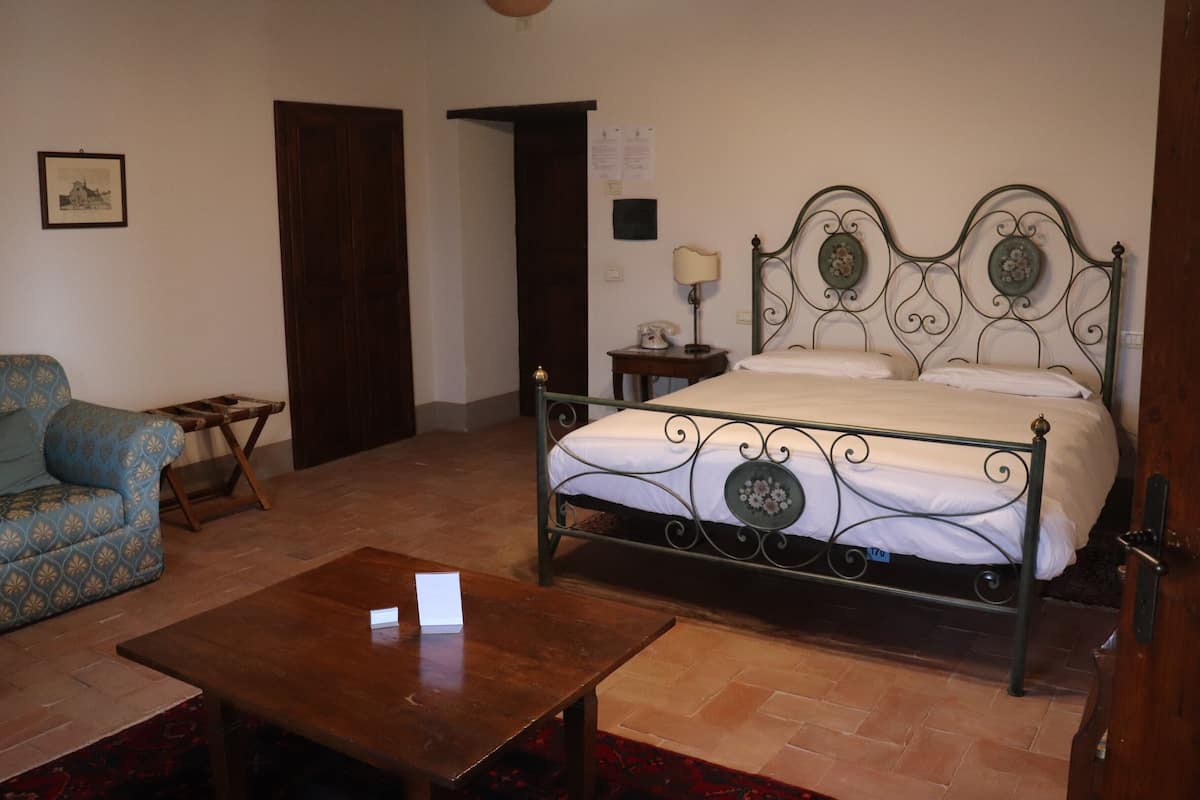 Um quarto com cama, cadeira, mesa e porta.