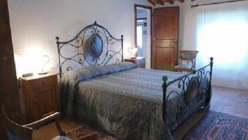 Quarto com estrutura de cama de metal, cabeceira de madeira e mesa de cabeceira com abajur.