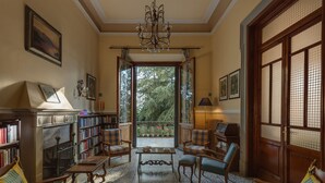 Uma biblioteca acolhedora com estantes de livros, assentos confortáveis e uma janela ampla com vista para o verde.