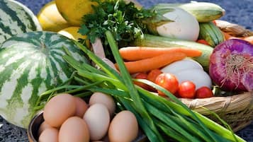 Diversos vegetais e frutas frescas, incluindo melancia, cenouras, tomates, cebolas e ovos.