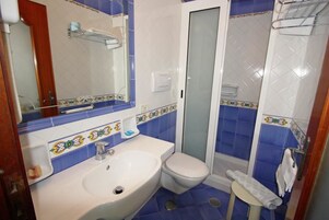Uma casa de banho com lavatório, sanita e chuveiro.