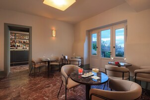 Quarto de hotel com área de bar, diversas opções de assento e uma grande janela com vista.