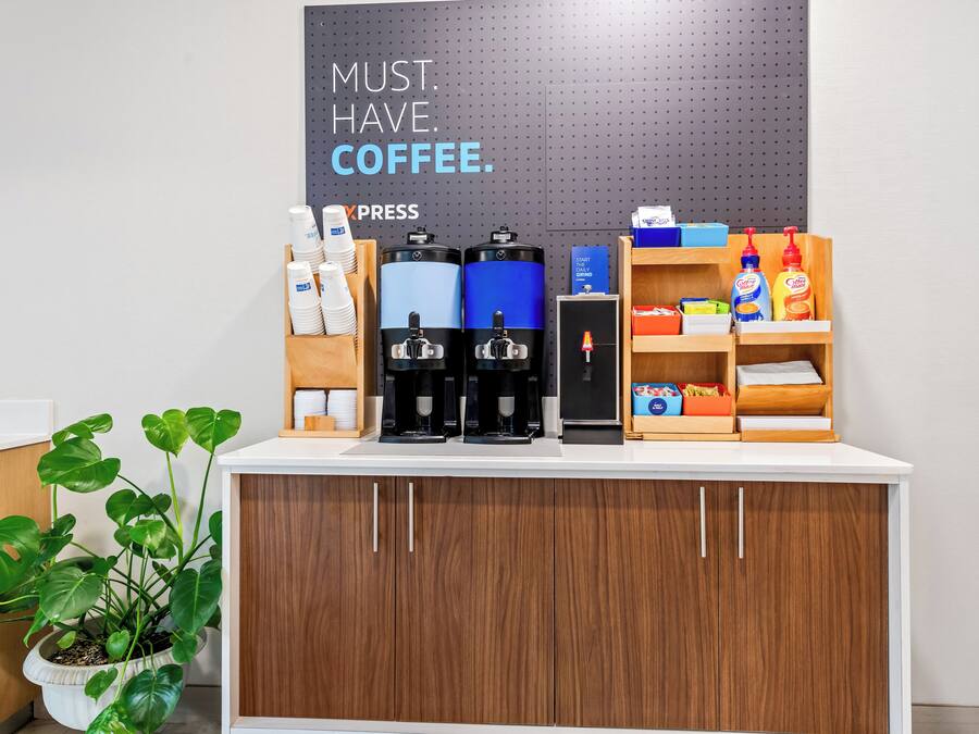 Um espaço de café com uma placa que diz 'MUST. HAVE. COFFEE.' e uma prensa francesa.