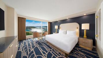 Quarto de hotel com uma cama grande, duas mesas de cabeceira, uma escrivaninha e uma cadeira.