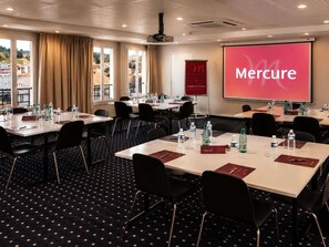 Uma sala de conferências com mesas, cadeiras, garrafas de água e uma tela de projetor exibindo 'Mercure'.