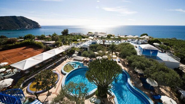 Um resort com várias piscinas, áreas de estar ao ar livre e vista para o mar.